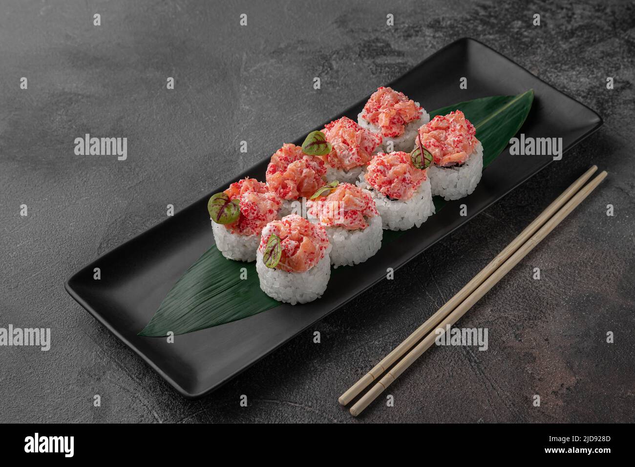 set of rolls with salmon, red flying fish caviar and green bamboo leaf ...