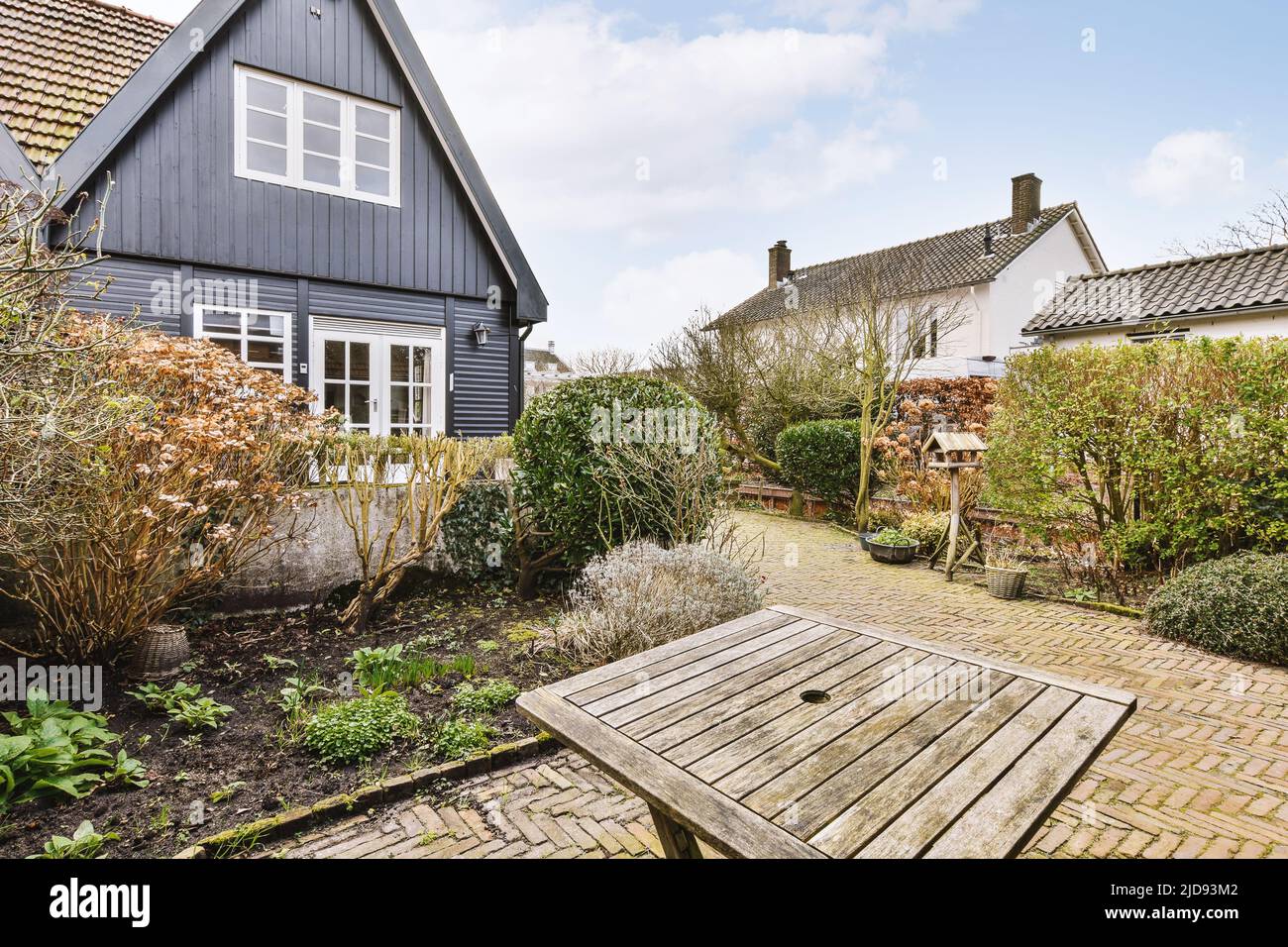 Neat paved patio with sitting area and small garden near wooden fence ...