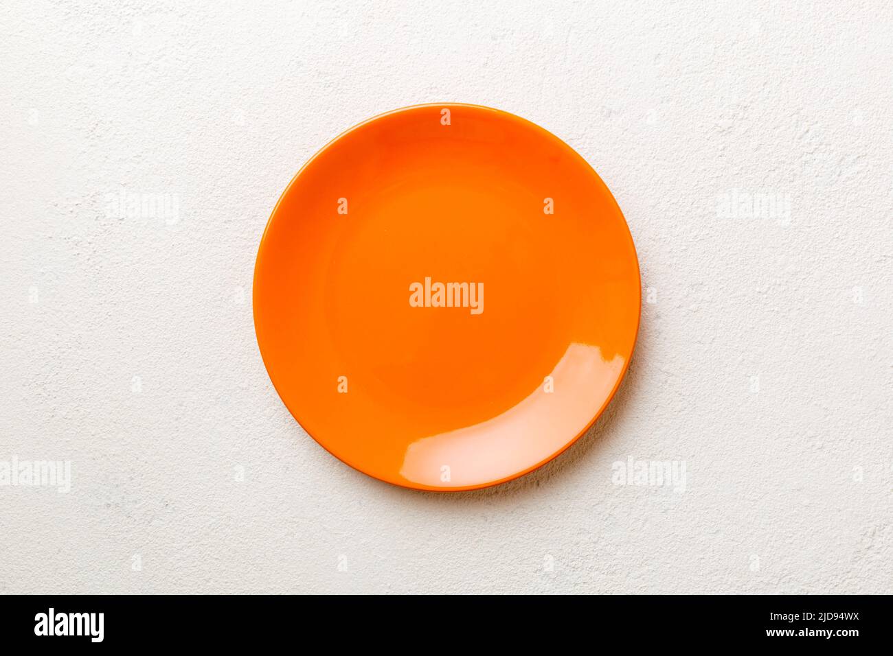 Top view of empty orange plate on cement background. Empty space for ...