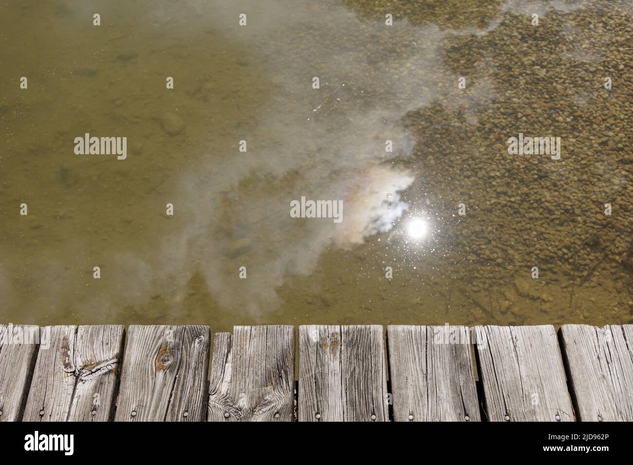 view from an old wooden pier into lake water with reflections mixed ...