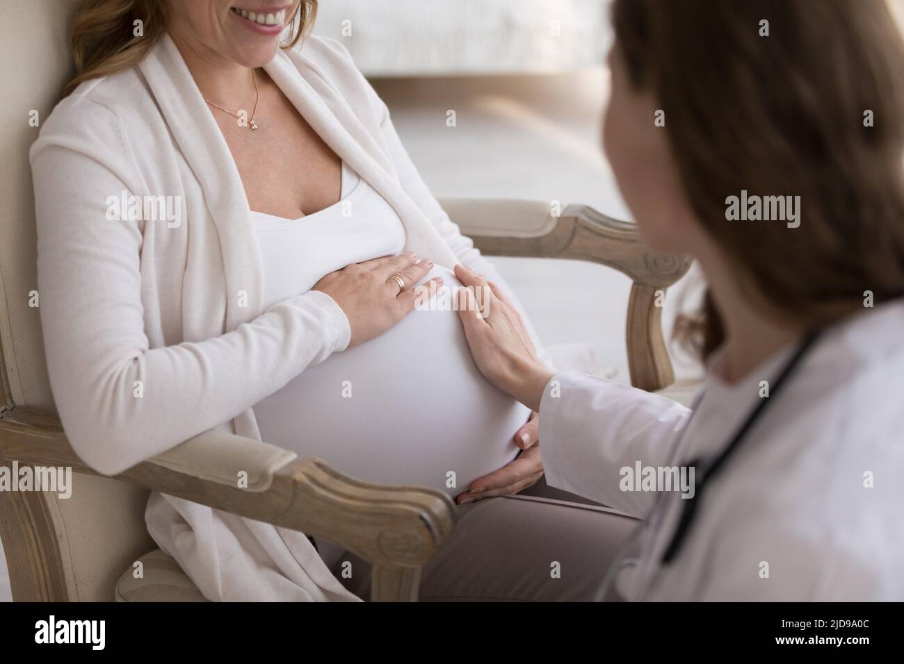 Obstetrician doctor touching belly of pregnant woman, closeup cropped ...