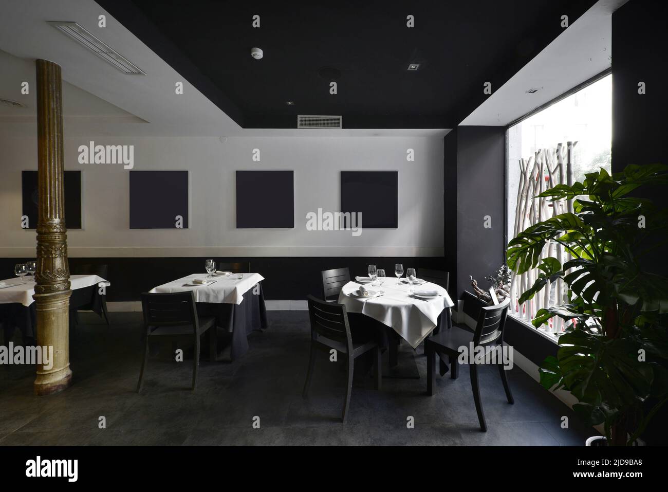 Dining room of a restaurant with tableware set, window with plants and ...
