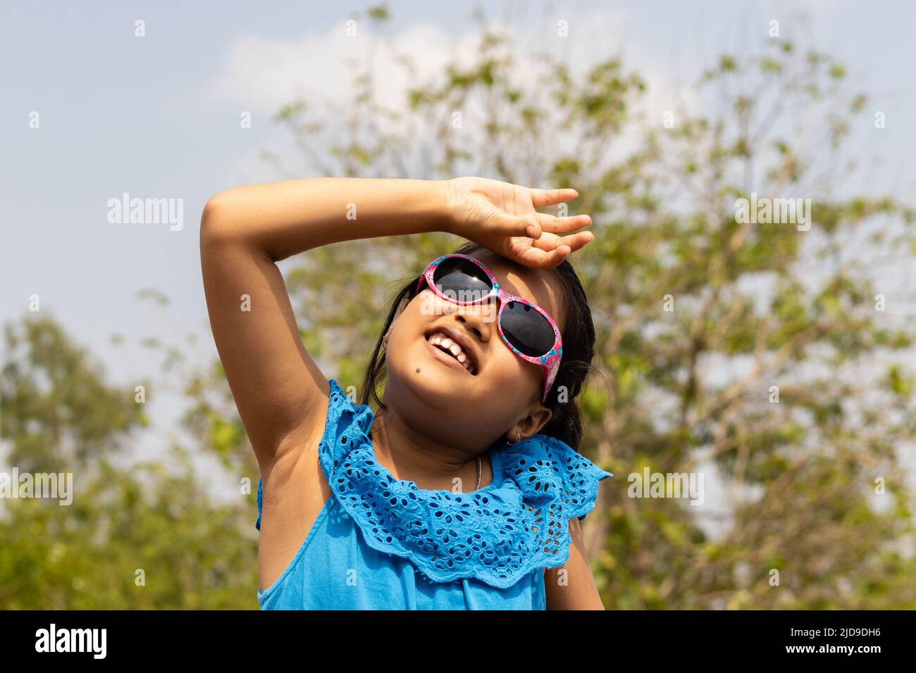 An Indian girl wearing sunglasses looking at the Sun in summer Stock ...