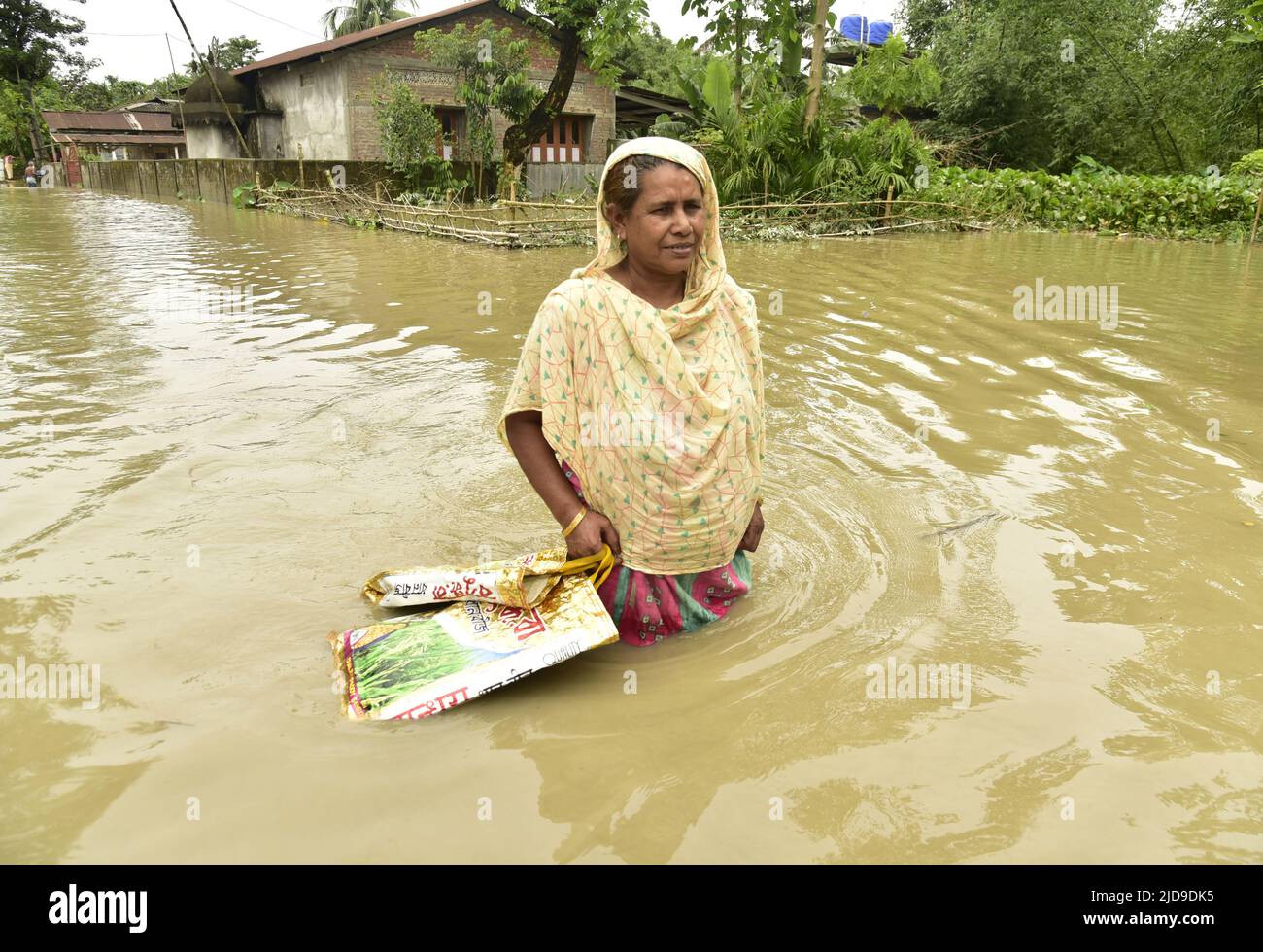 Guwahati, Guwahati, India. 19th June, 2022. A woman wades through the flood water at Rangia in ...