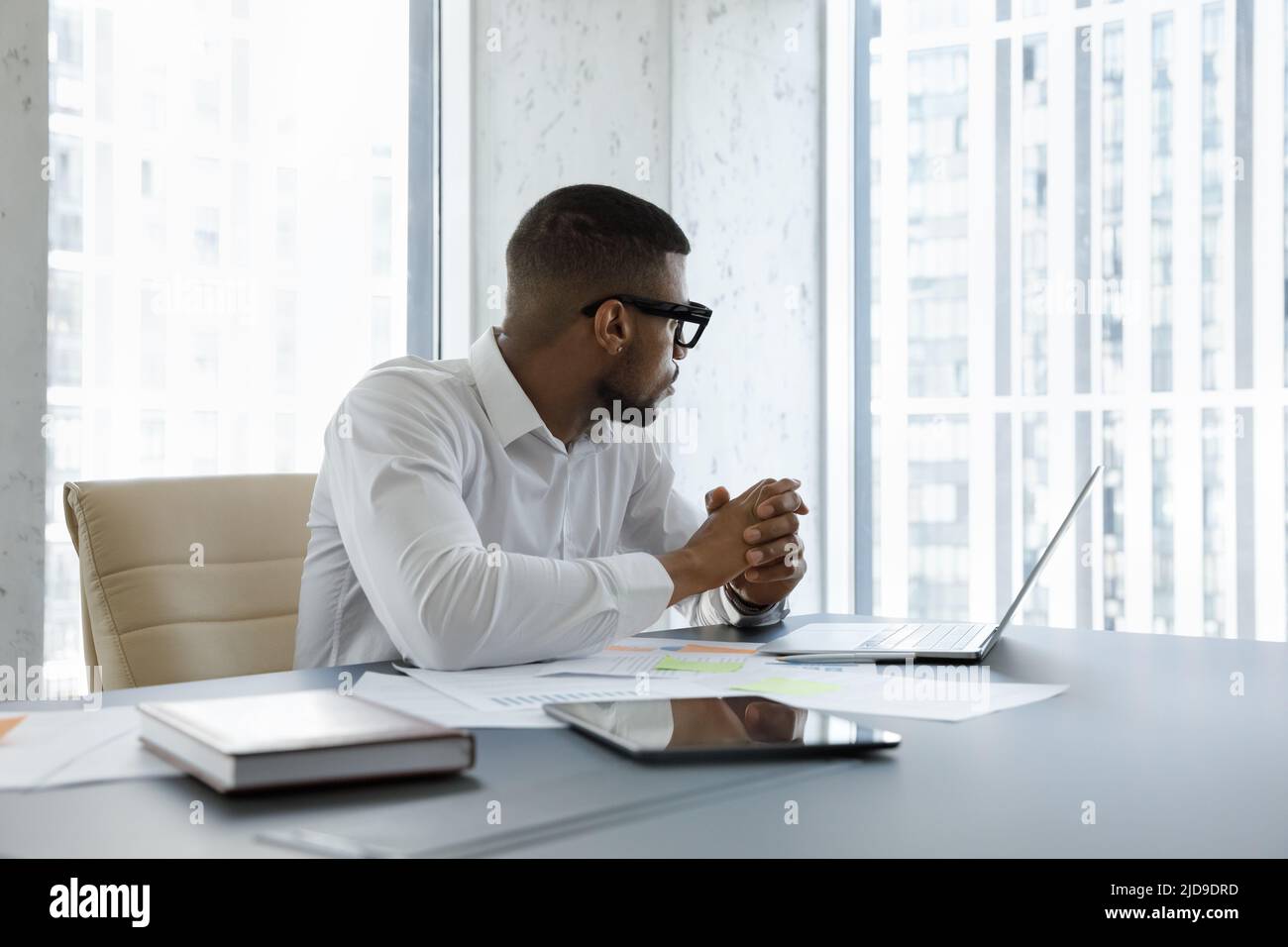 African businessman sit at workplace staring out window looks ...