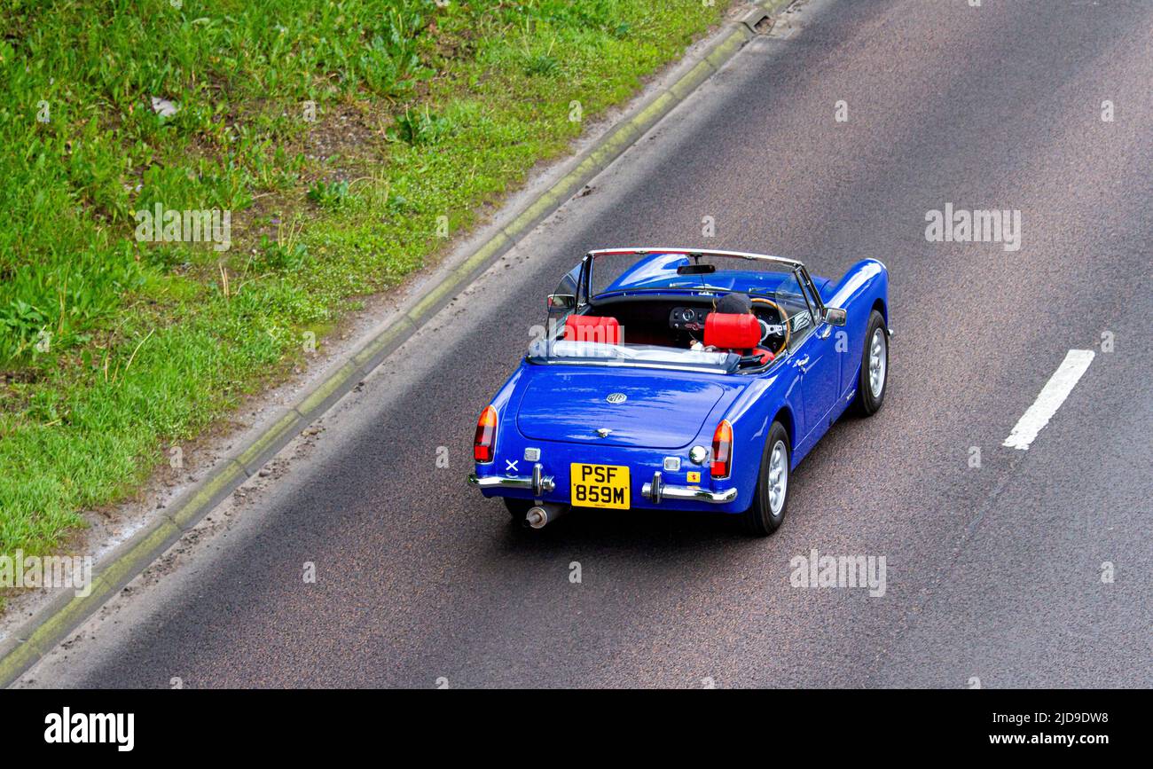 A blue convertible MG 1973-74 registration sports car with roof down is ...