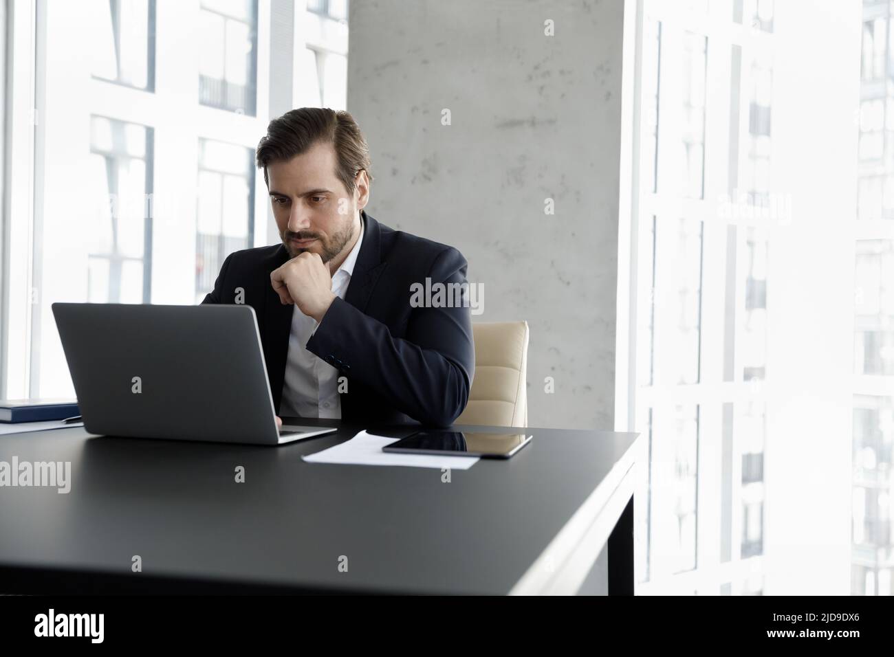 Serious focused businessman using laptop working seated at modern ...