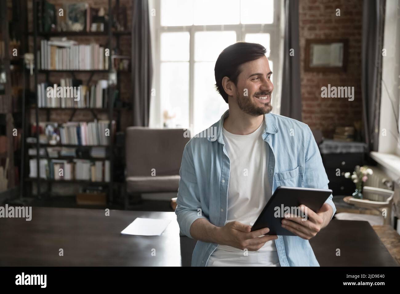 Businessman use apps on digital tablet staring aside feels satisfied ...