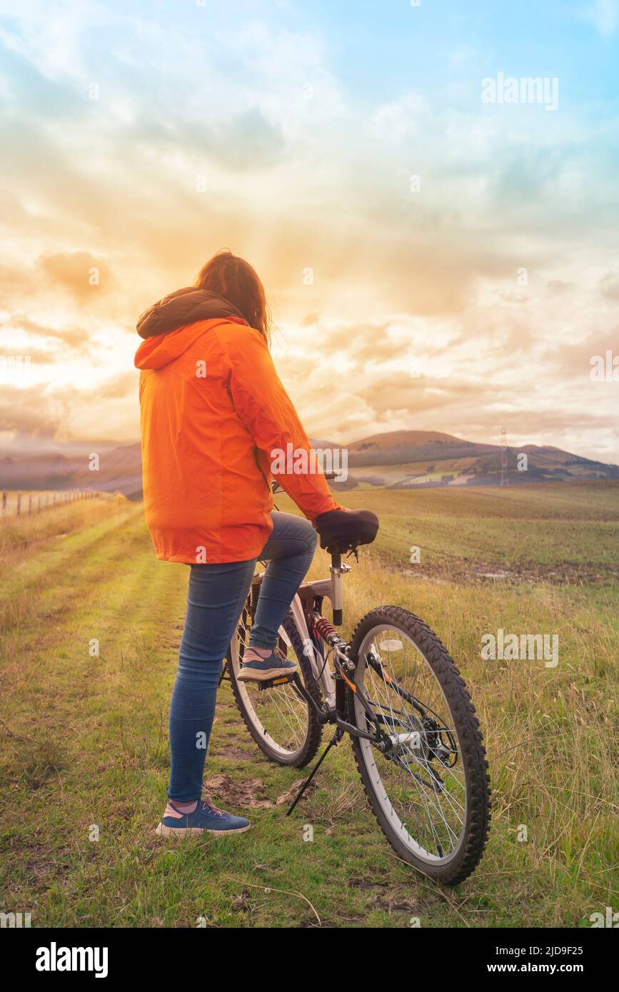 Young Hispanic woman wearing orange jacket and blue pants resting ...