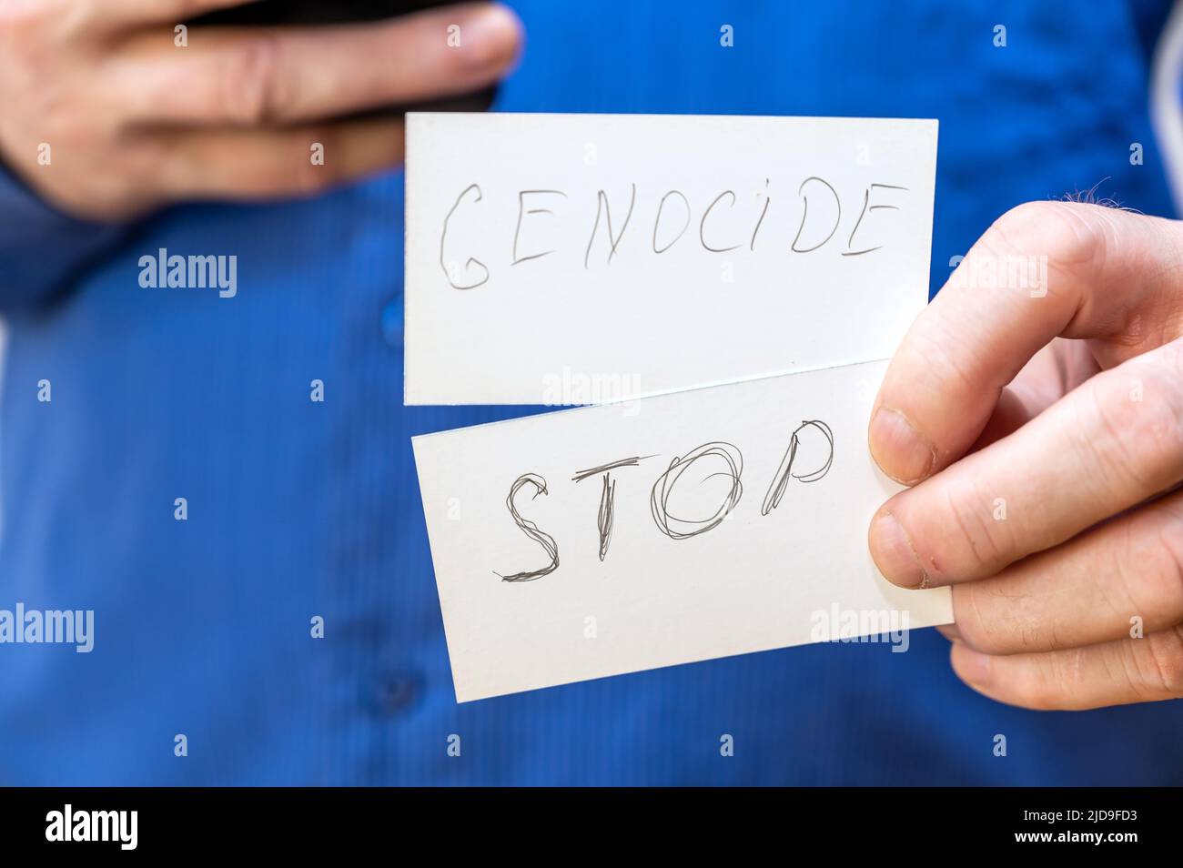 Stop Genocide. Inscription in jagged gray letters on paper. Man holding ...