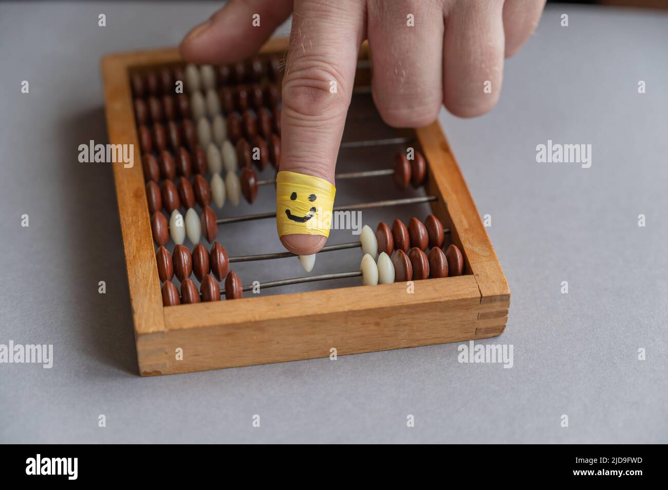 A man makes calculations on small wooden abacus. The index finger is ...
