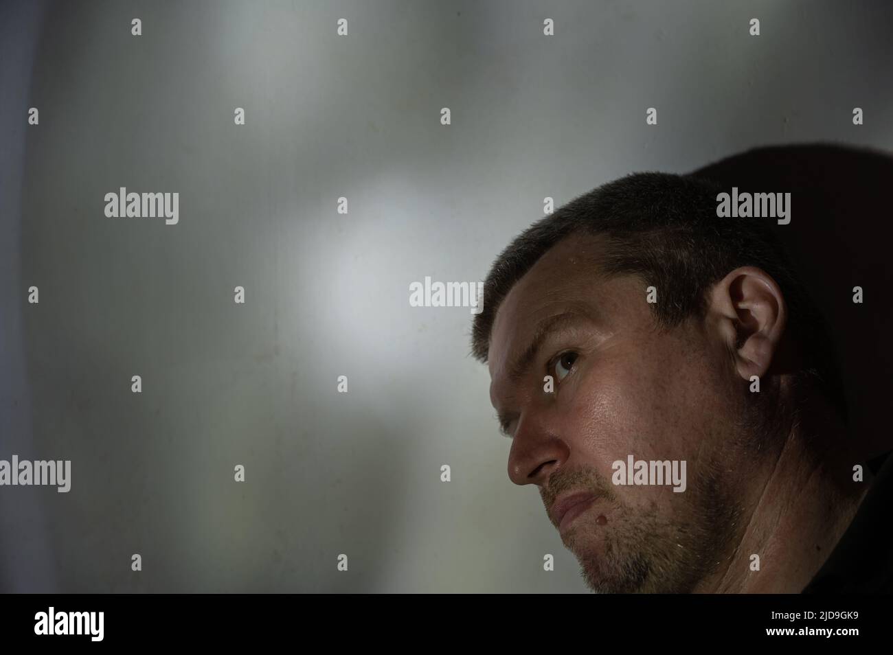 Portrait of tired middle-aged man against gray-green wall. Unshaven man ...