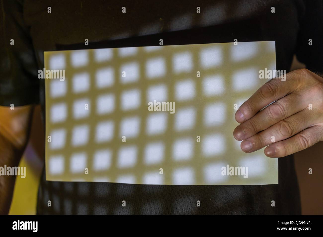 Middle section of mature man holding rectangular sheet of white paper ...