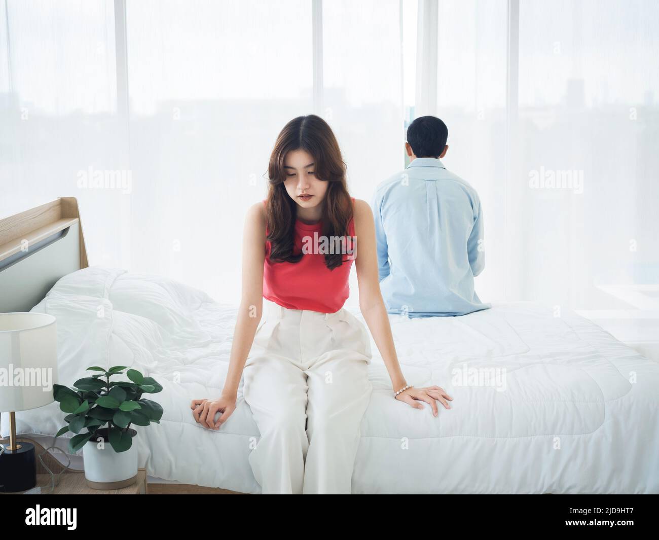 The anxiety of Asian couple lovers on the bed. Sad young woman and man ...