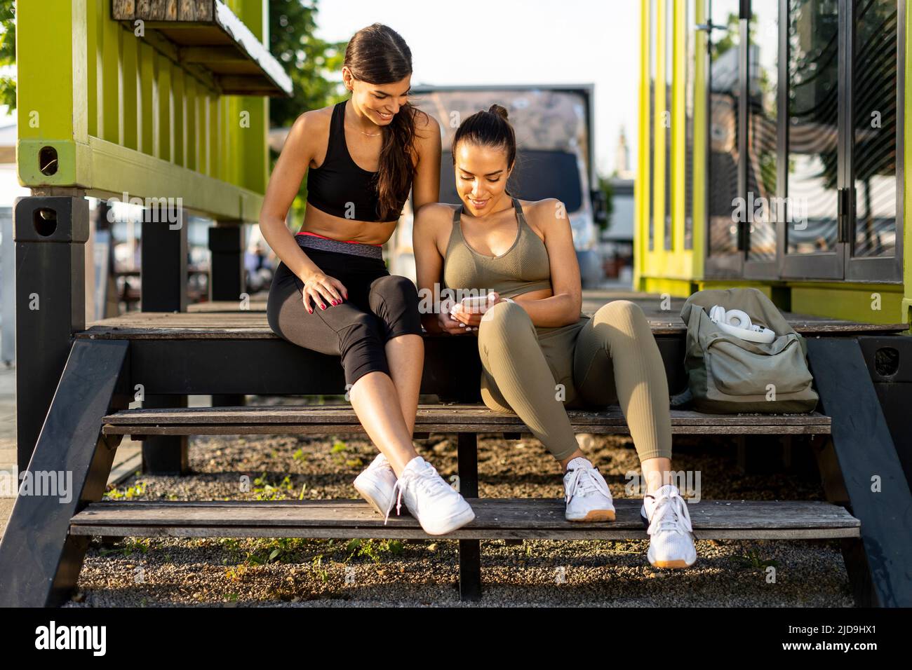 Pretty Young Women In Sportswear Looking At Mobile Phone After Exercise