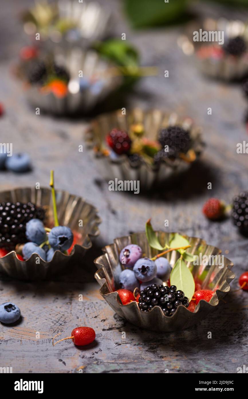 Assorted berries in metal baking dishes on a gray background Stock ...