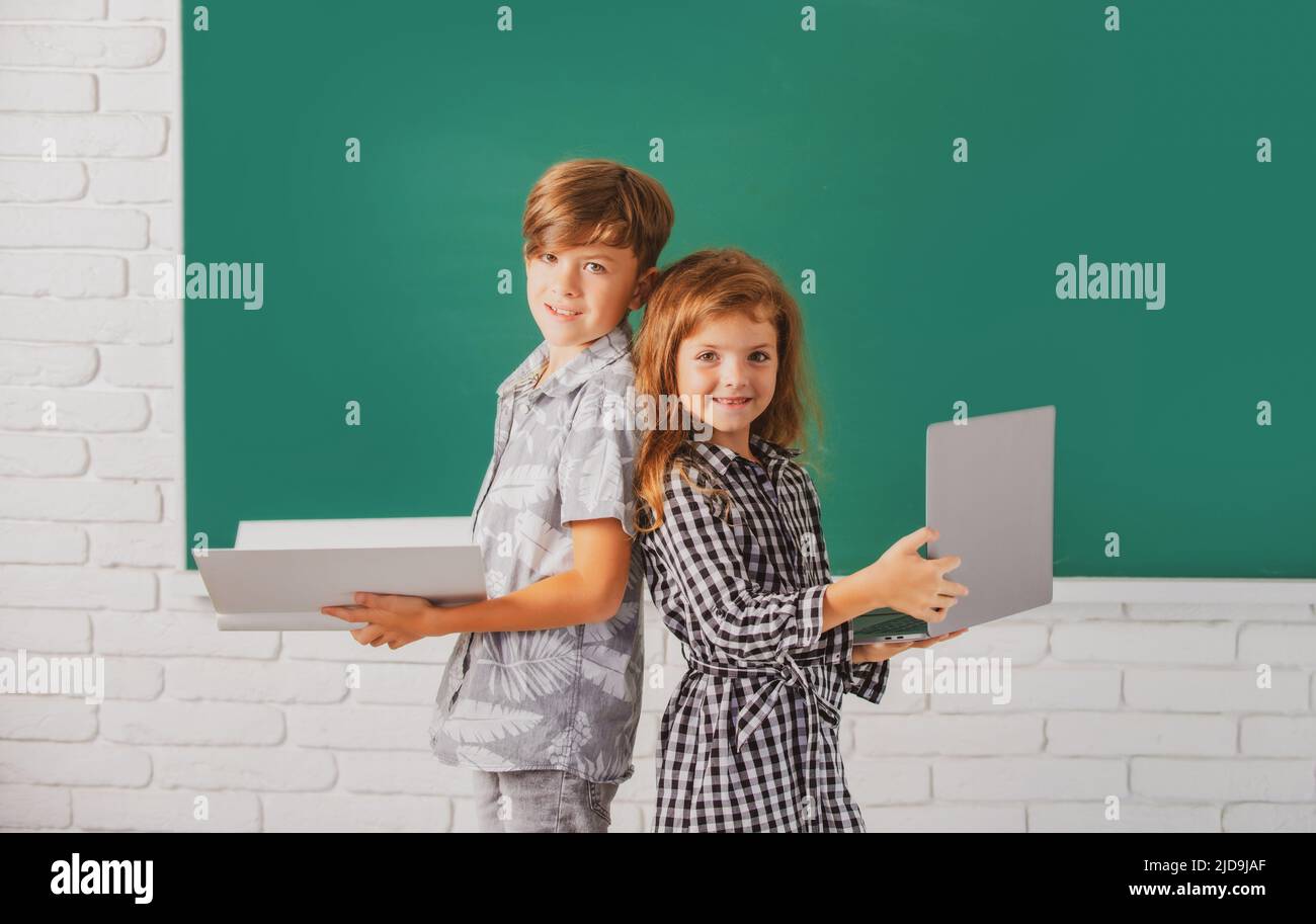 Portrait of children boy and girl with laptop computer and book at ...