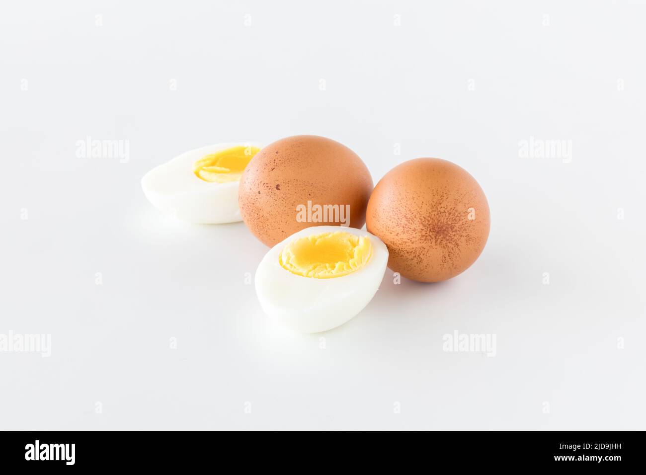 Whole and sliced cooked eggs against a white background Stock Photo - Alamy