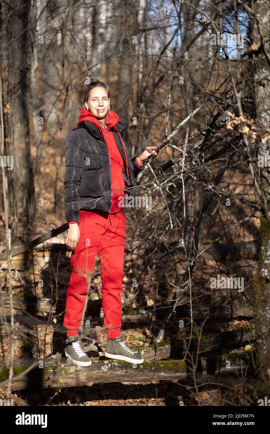 Young tall woman crossing moat on log while walking in forest far away ...