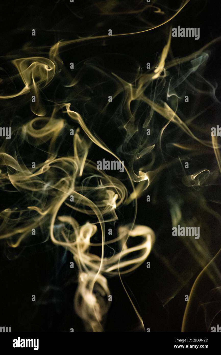 Swirling, ascending smoke pattern with a yellowish gold color on a ...