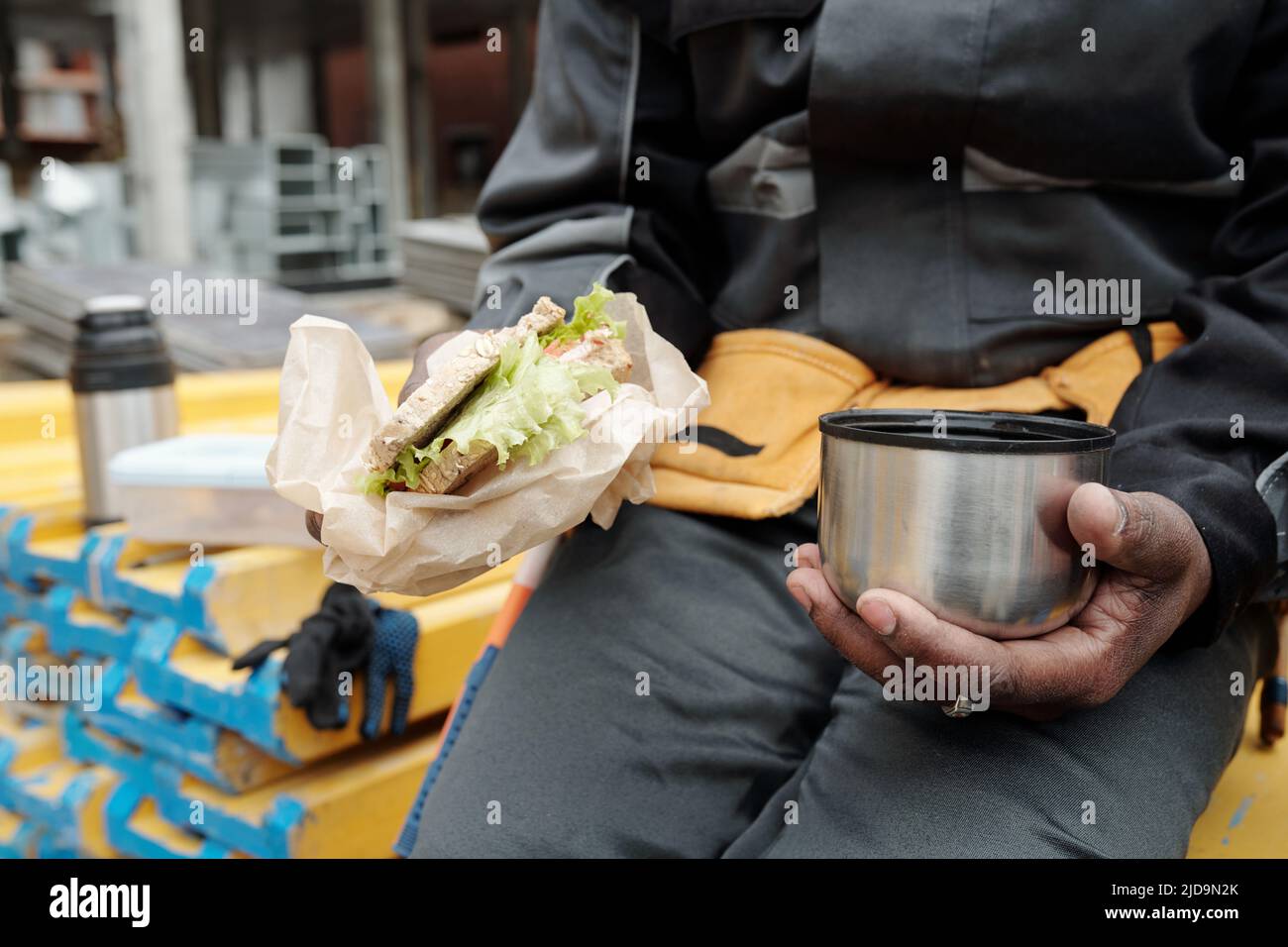 Hand of African American worker of construction site holding cup with ...