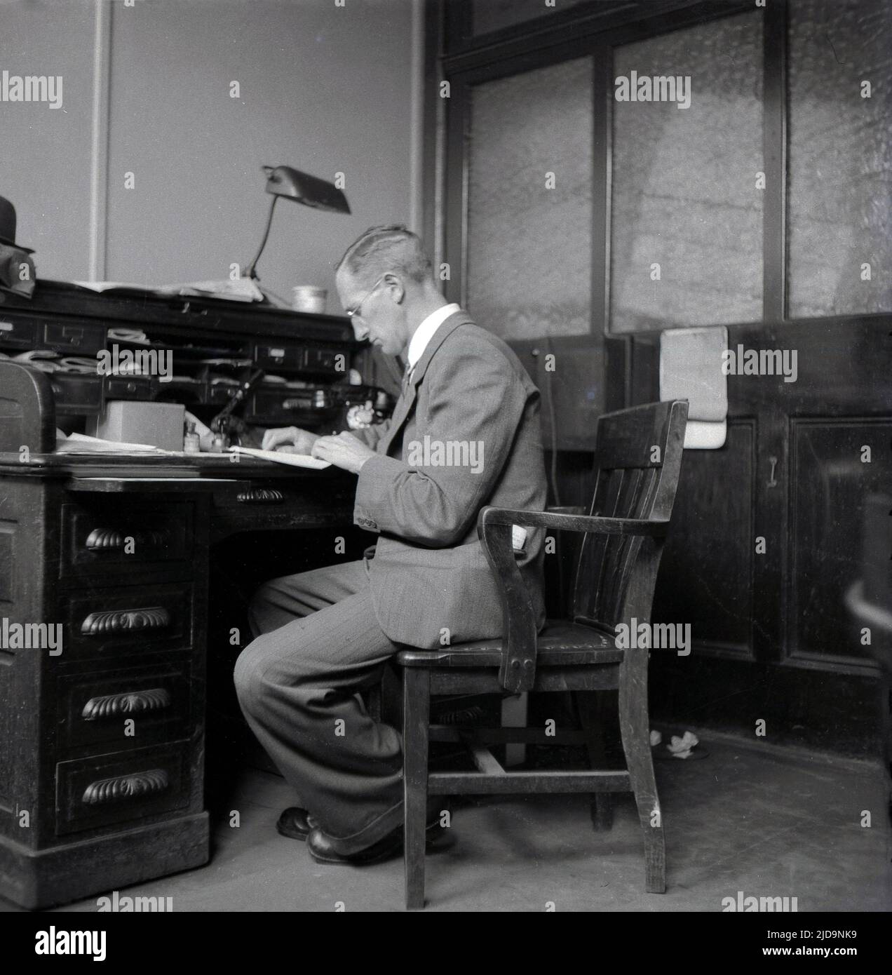 1940s Historical An English Gentleman In A Suit And Tie Sitting At A