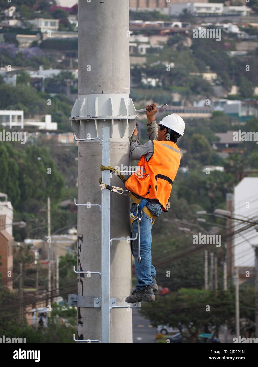 A construction worker installing a pole for a mobile telephone antenna ...