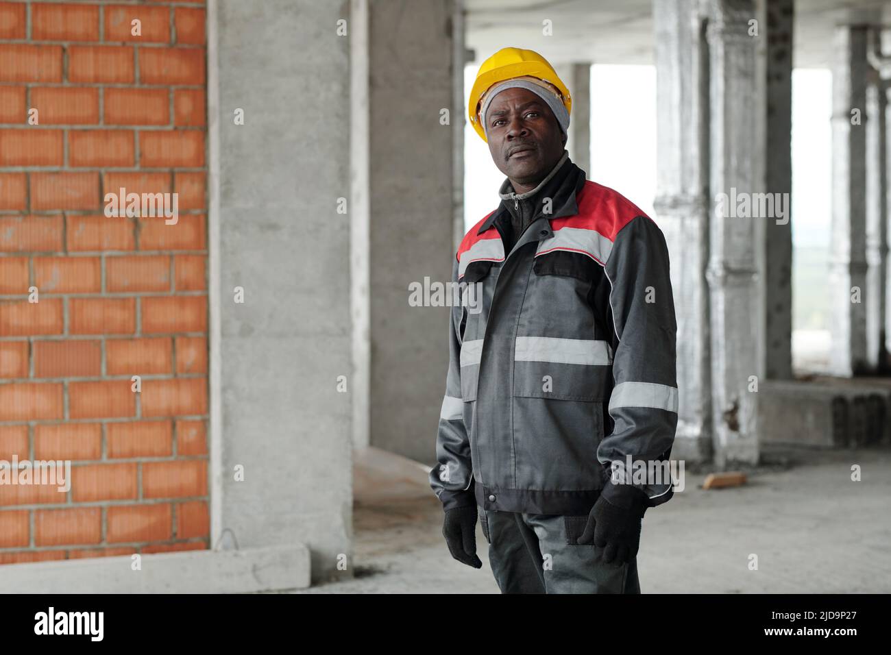 Aged African American builder or foreman in uniform and hardhat ...