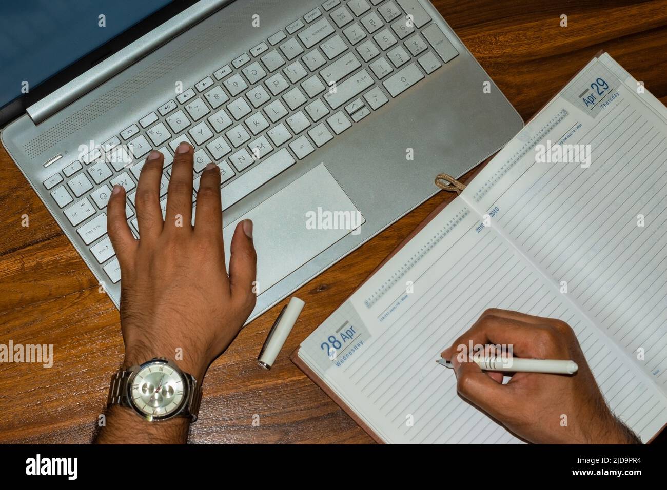 Top view of businessman typing on laptop while writing on a diary on ...