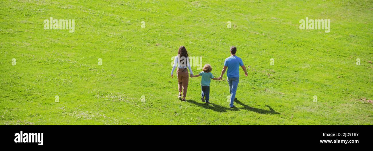Back view of parents playing with child outside in park. Banner ...