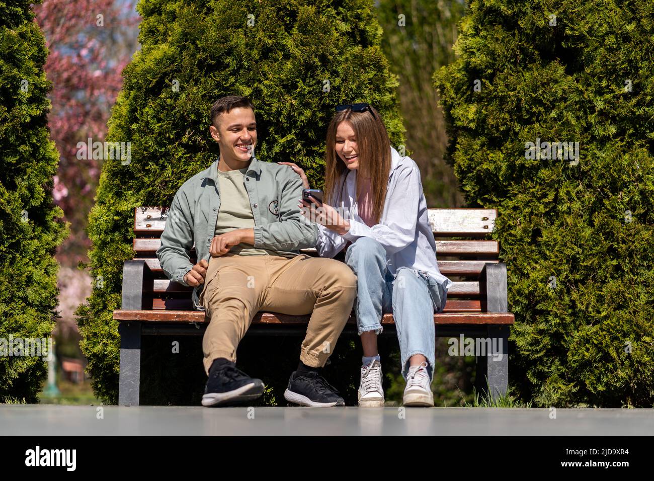 Happy casual couple talking looking each other sitting in a park with a ...
