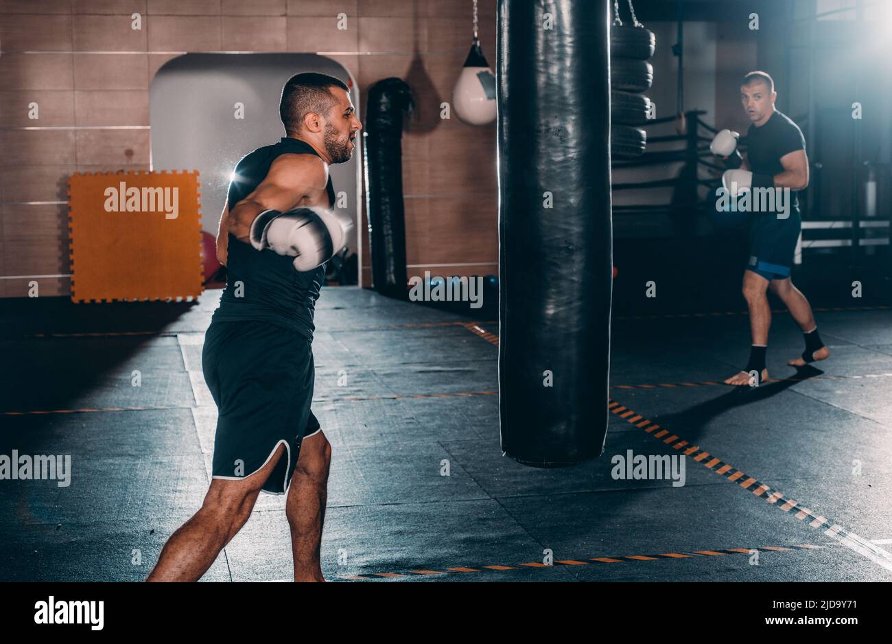 Heavy male kick boxer hitting a huge punching bag at a boxing studio ...