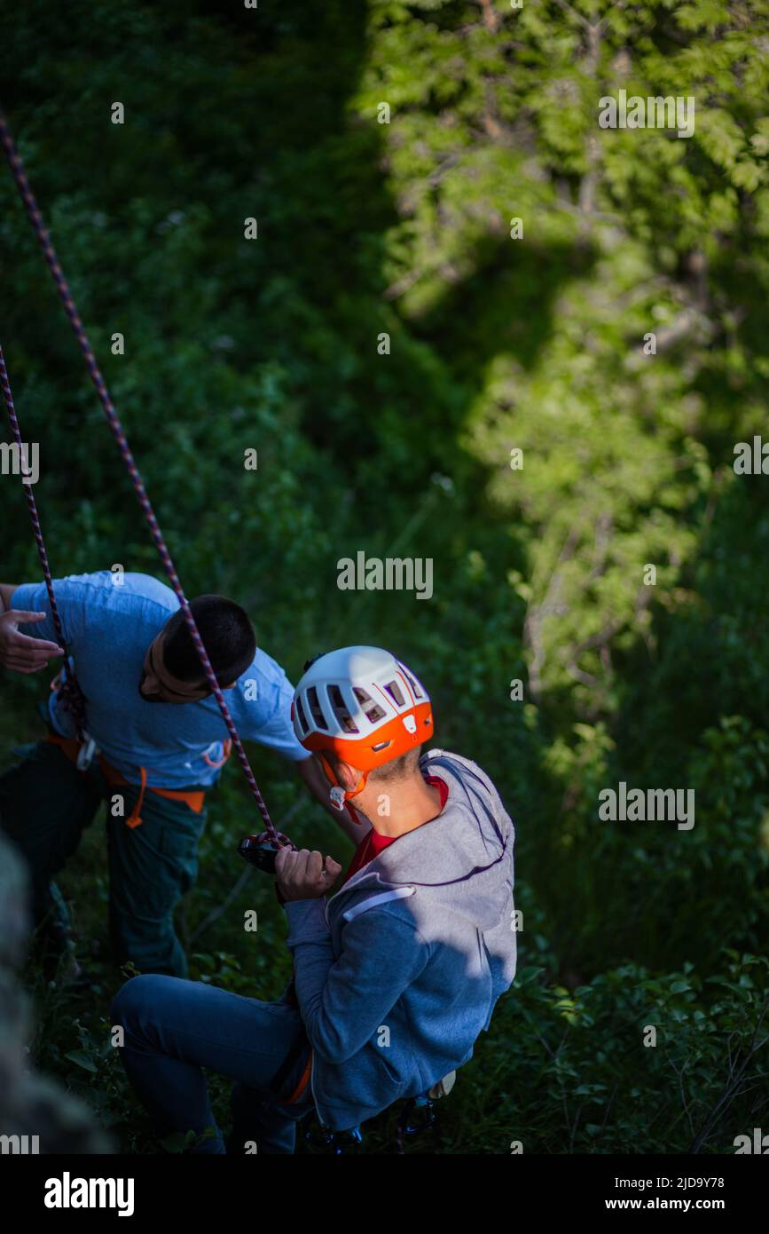 Two rockclimbers looking down at a steep mountain with their climbing ...
