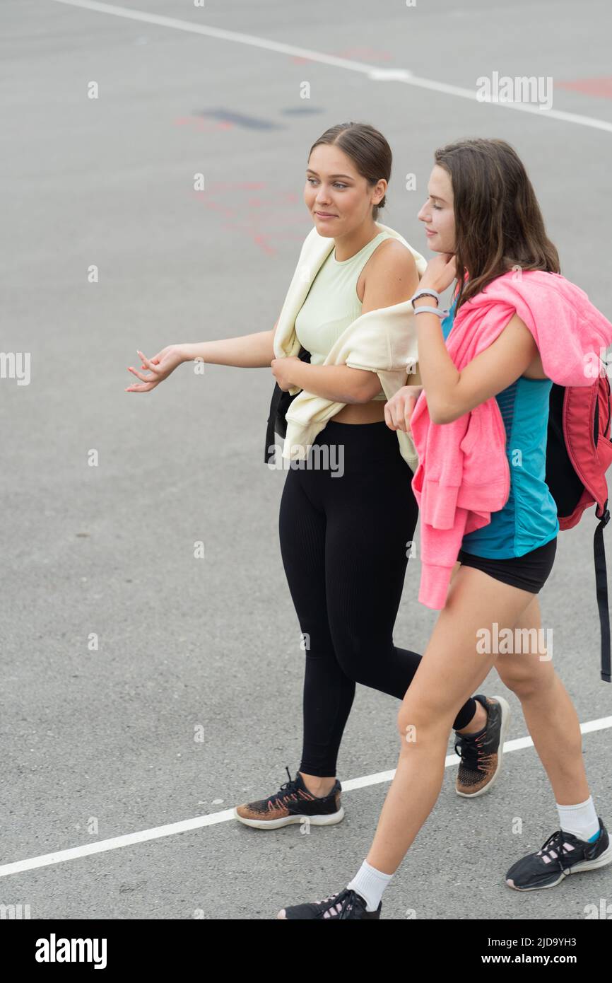 Two girls are smiling and talking while walking together Stock Photo ...
