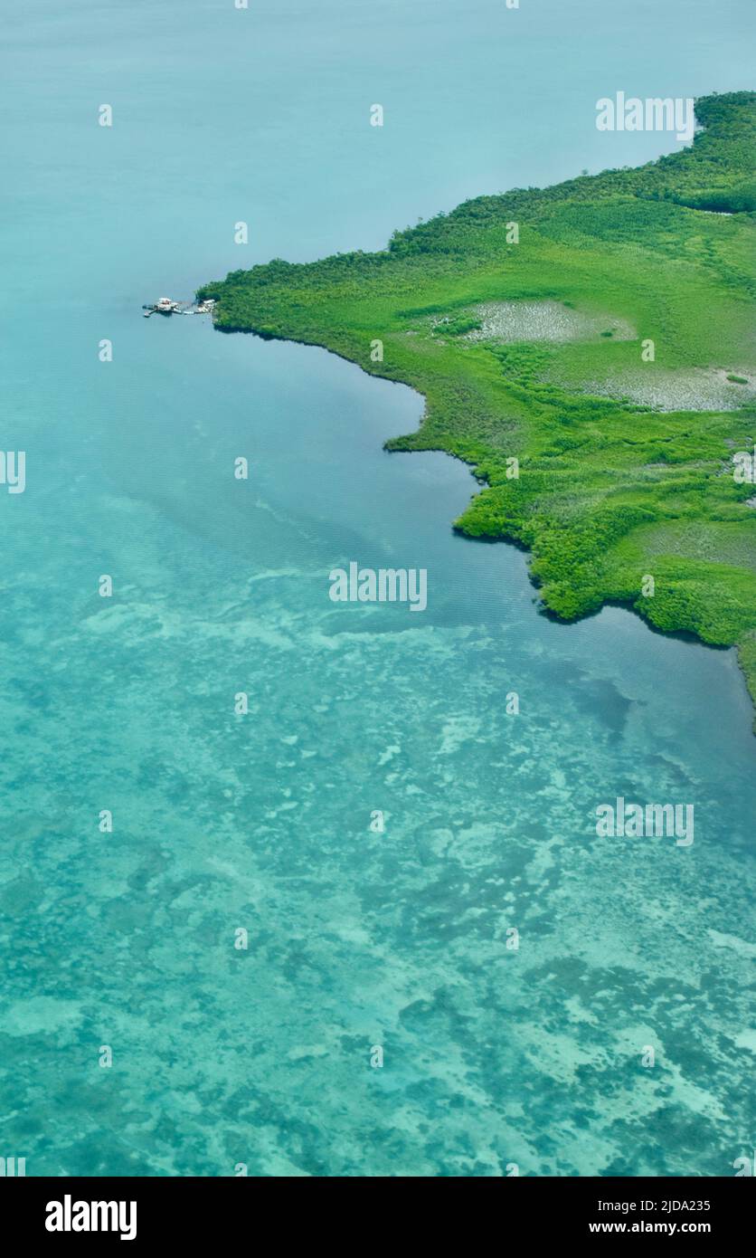 An aerial view of part of an atoll and the clear, blue waters of Belize ...