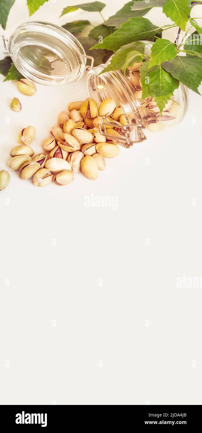 Vertical, food banner with a glass jar with roasted, salty pistachios ...
