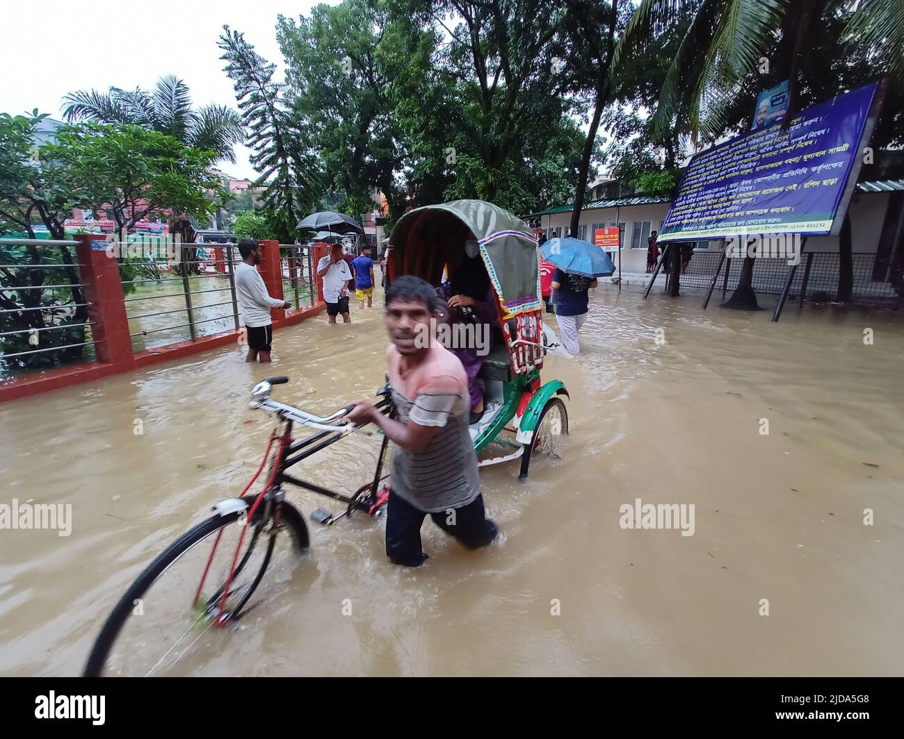 Sylhet, Bangladesh. 19th June 2022. People wade through flood water as they look for shelter ...