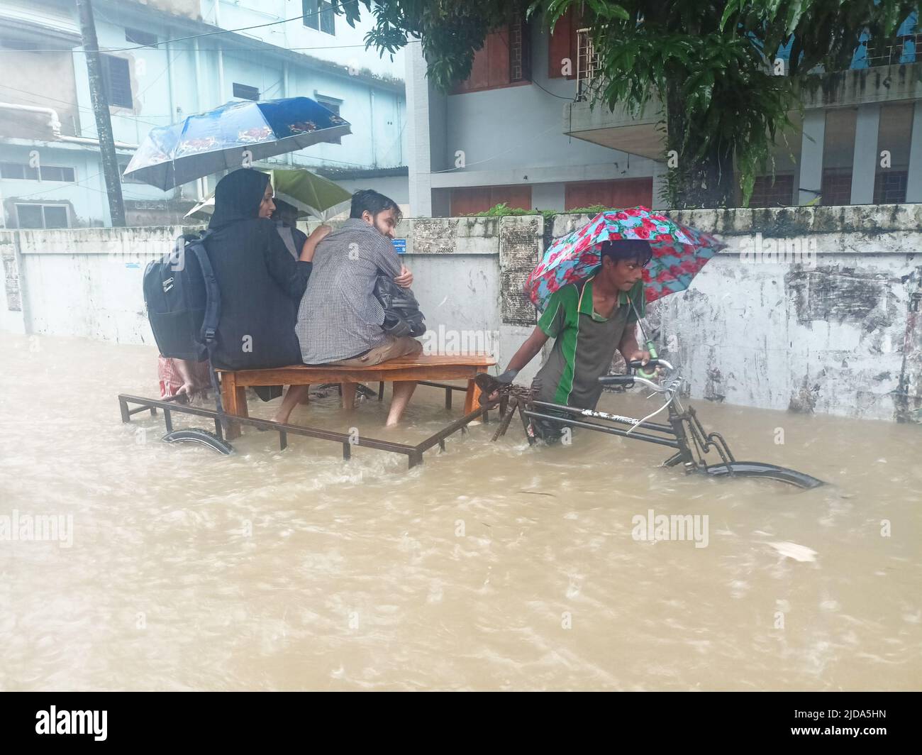 Sylhet, Bangladesh. 19th June 2022. People wade through flood water as they look for shelter ...
