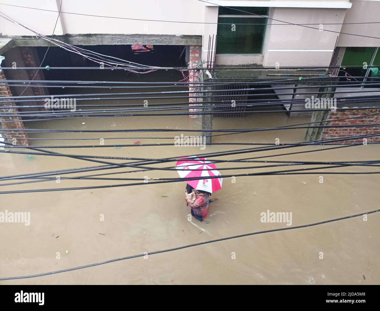 Sylhet, Bangladesh. 19th June 2022. People wade through flood water as they look for shelter ...
