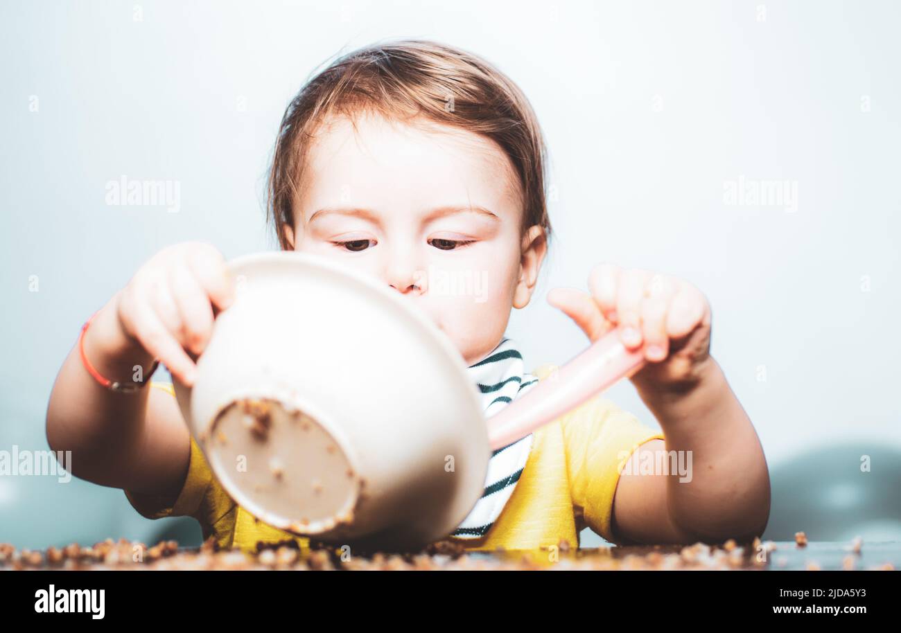 Happy baby child with a spoon. Baby eating. Kid plays in the kitchen ...