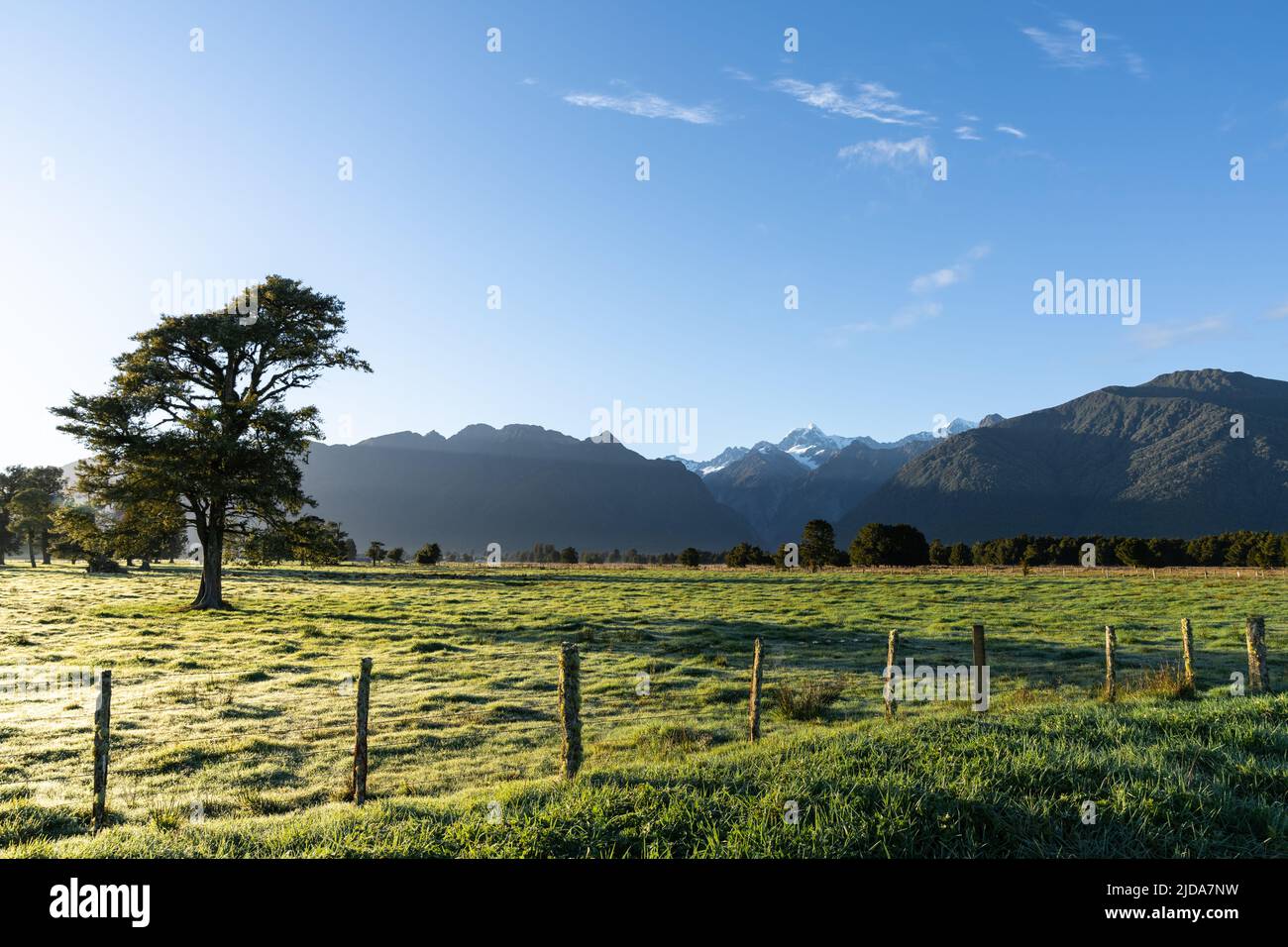 Mountains backdrop to New Zealand rural sunrise landscape over fence ...