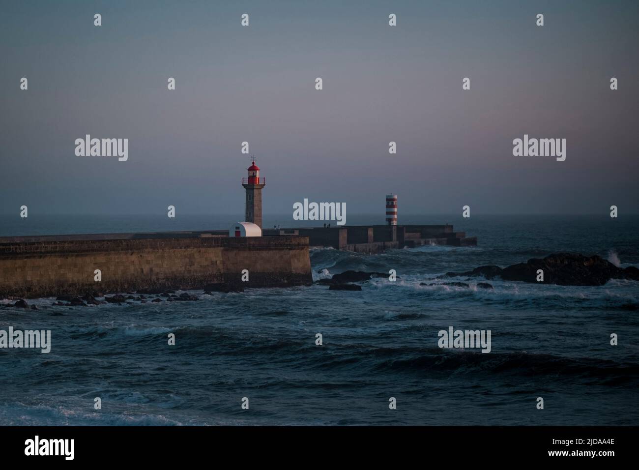 A pier with a lighthouse in the overcast evening ocean Stock Photo - Alamy