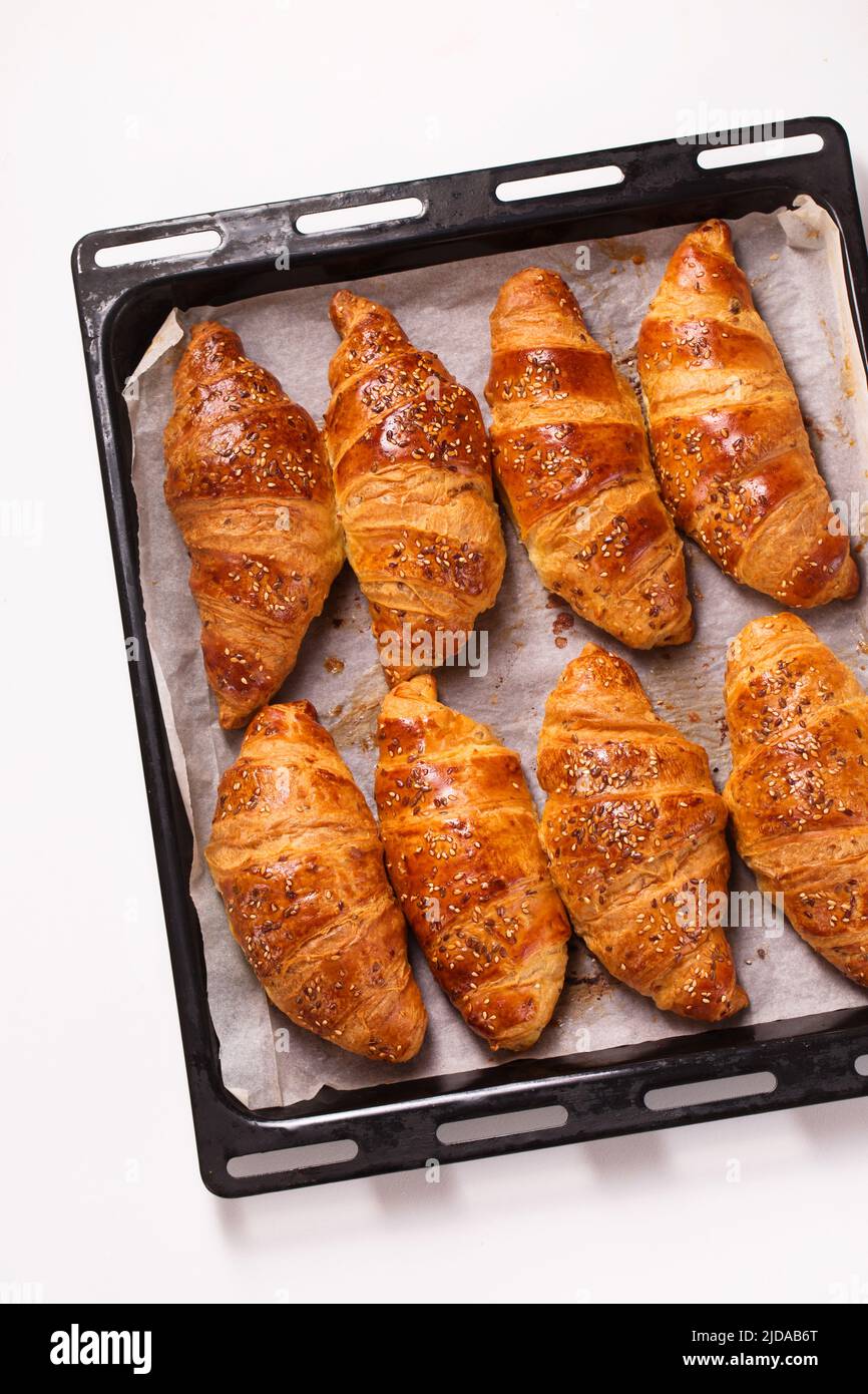 big croissants in a metal baking sheets on a white background, top view ...