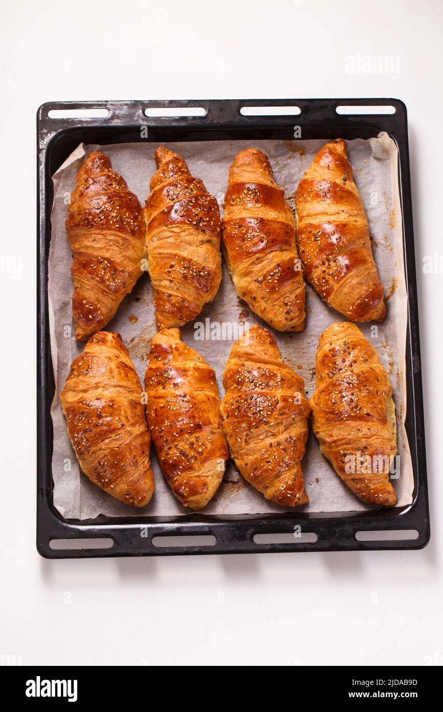big croissants in a metal baking sheets on a white background, top view ...