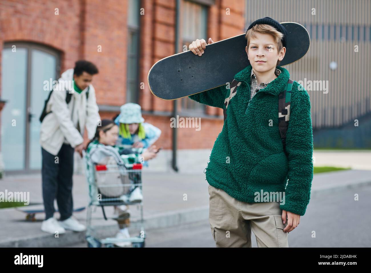 Portrait of skater boy holding his skateboard and looking at camera ...