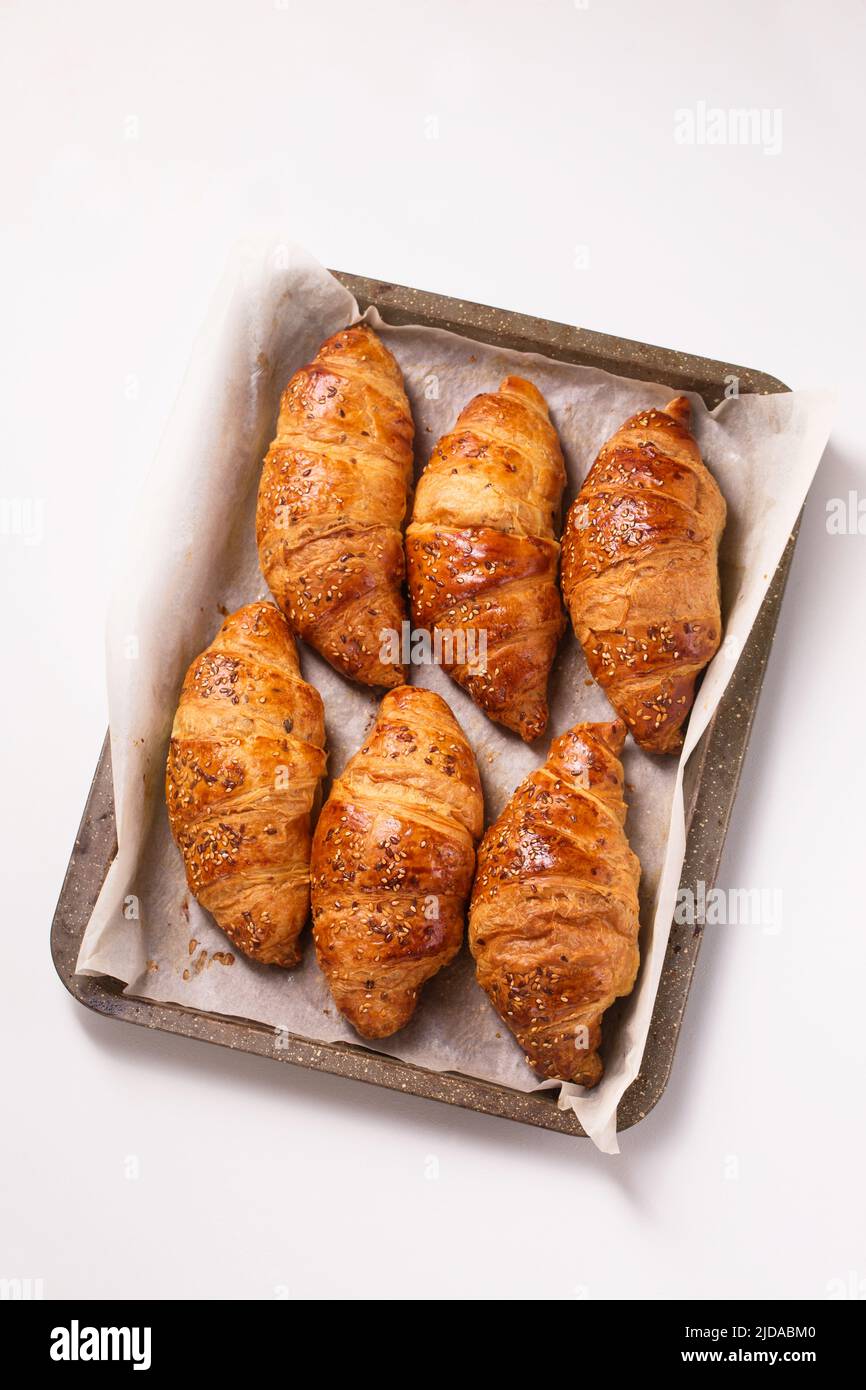 big croissants in a metal baking sheets on a white background, top view ...