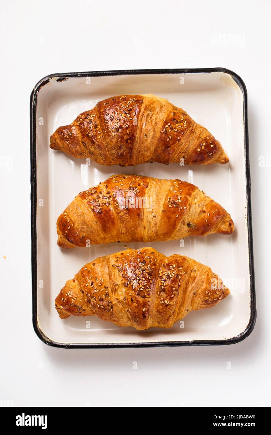 big croissants in a metal baking sheets on a white background, top view ...