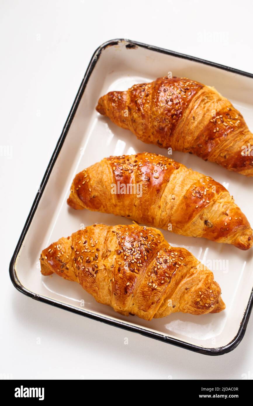 big croissants in a metal baking sheets on a white background, top view ...