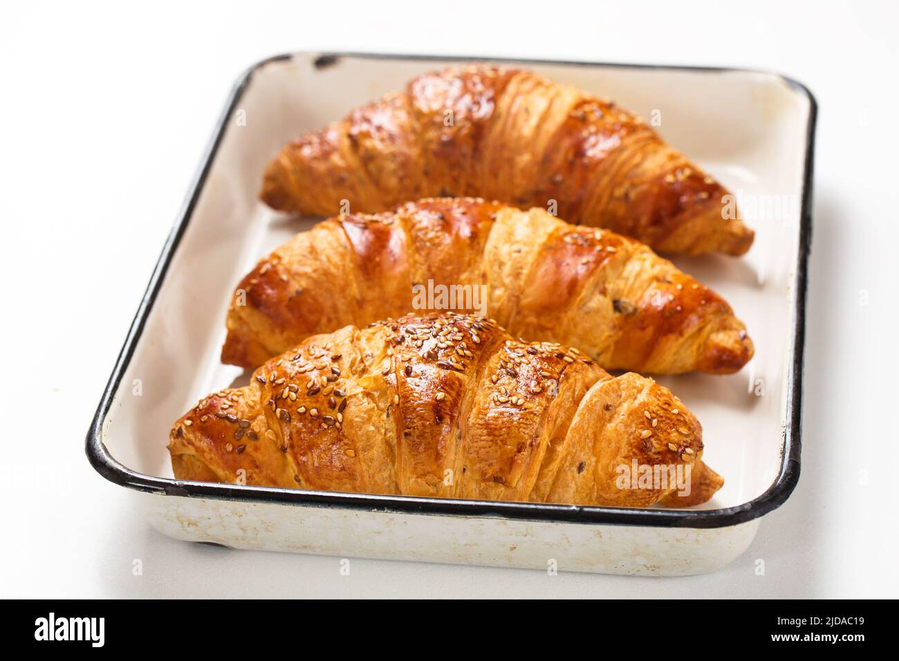 big croissants in a metal baking sheets on a white background, top view ...