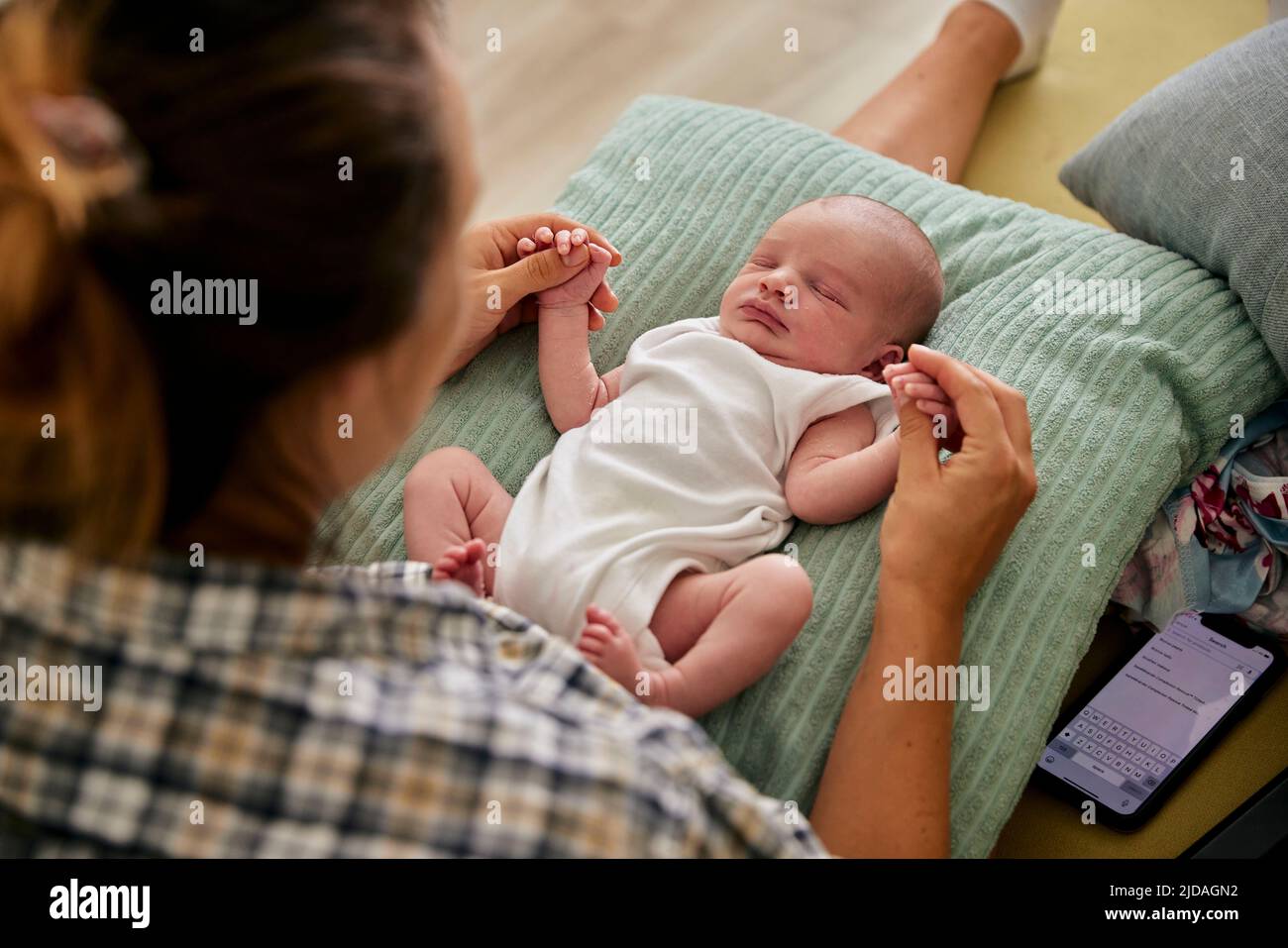 Mother holding hands of sleeping three month old baby boy lying on his ...